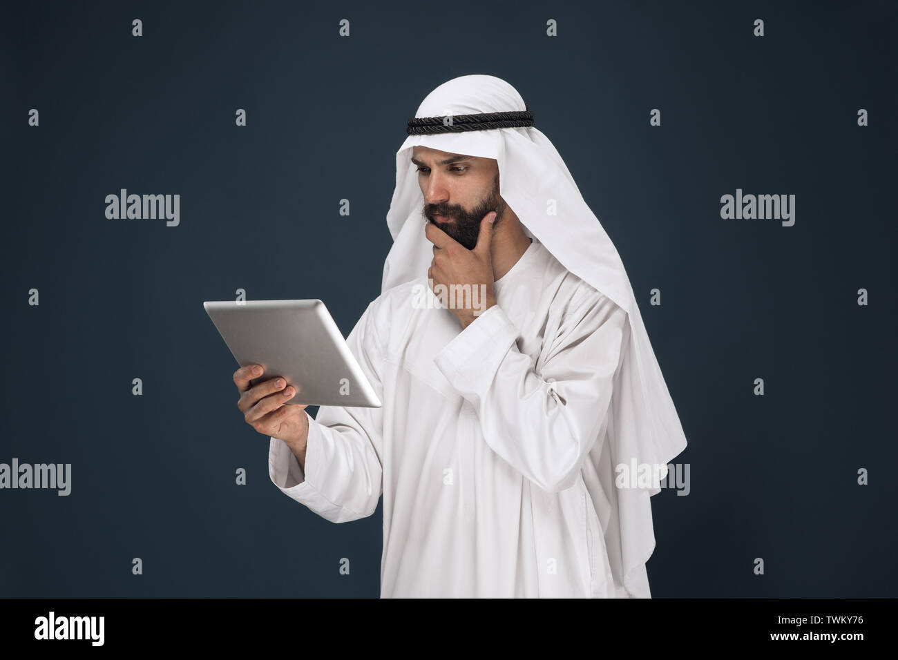 Half-length portrait of arabian saudi businessman on dark blue studio ...