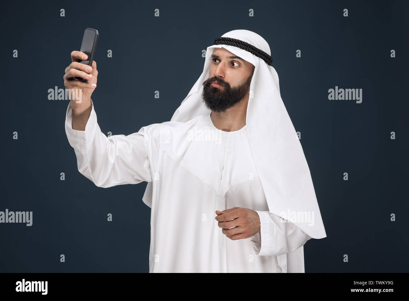 Half-length portrait of arabian saudi man on dark blue studio ...