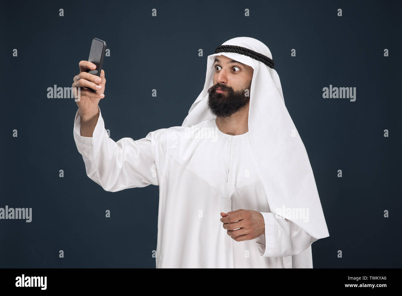Half-length portrait of arabian saudi man on dark blue studio ...