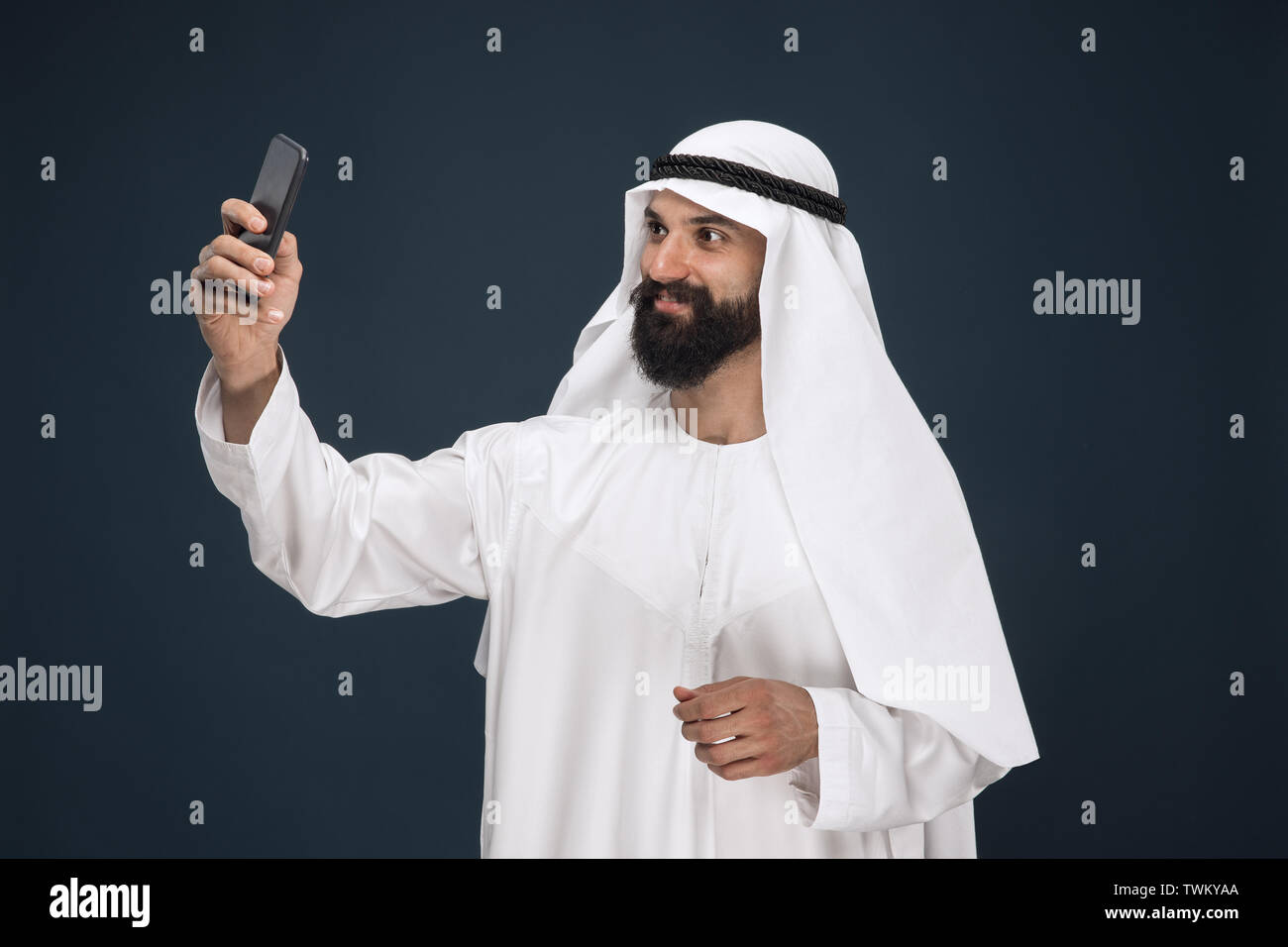 Half-length portrait of arabian saudi man on dark blue studio ...