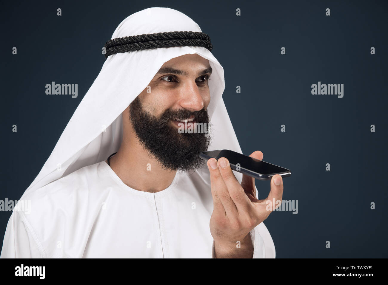 Half-length portrait of arabian saudi man on dark blue studio ...