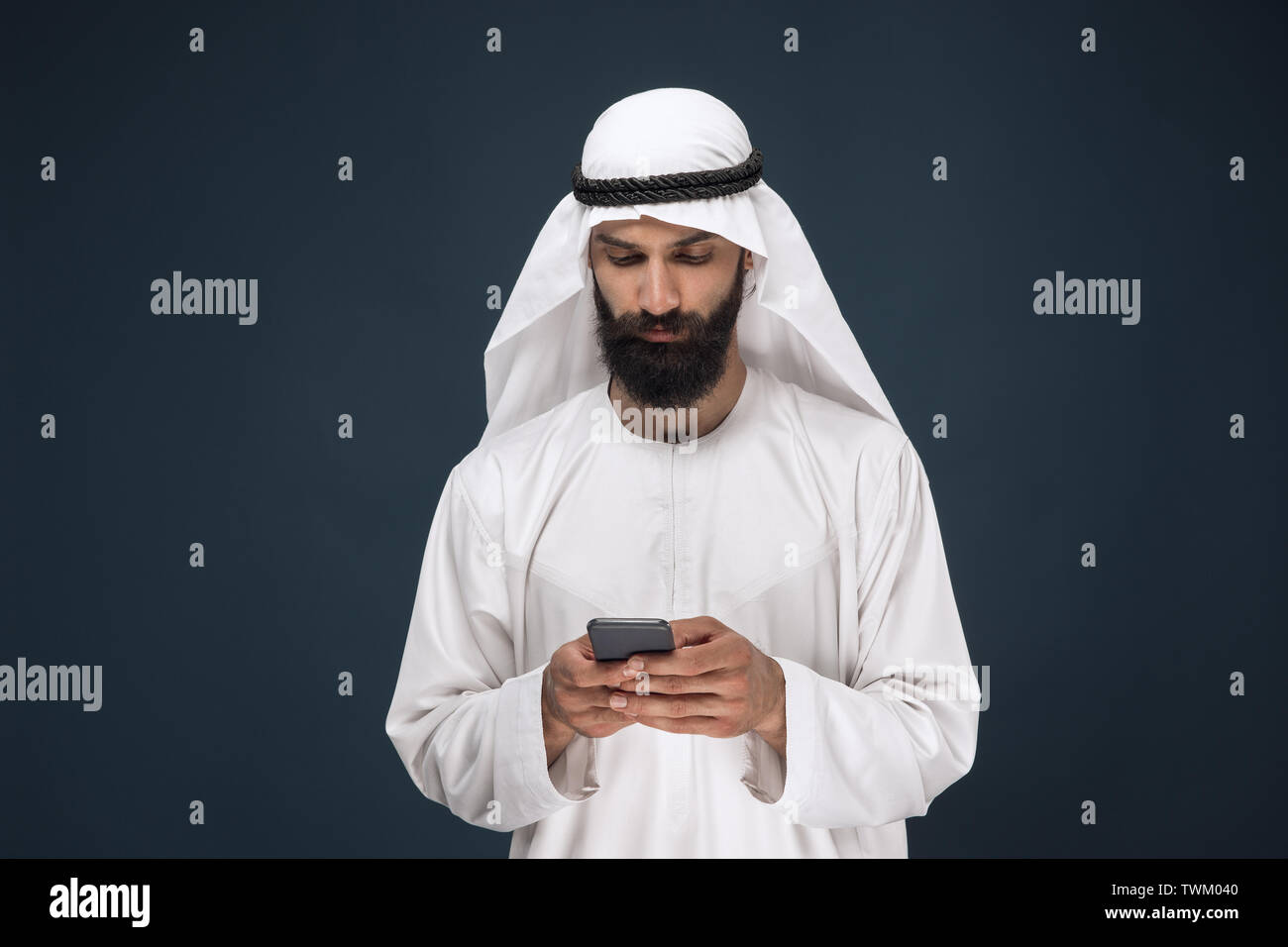 Half-length portrait of arabian saudi man on dark blue studio ...