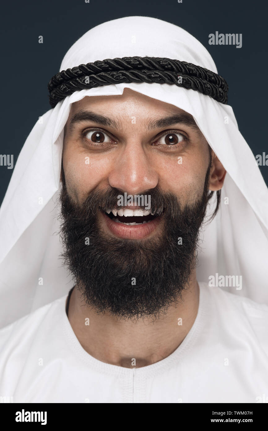 Close up portrait of arabian saudi businessman on dark blue studio ...