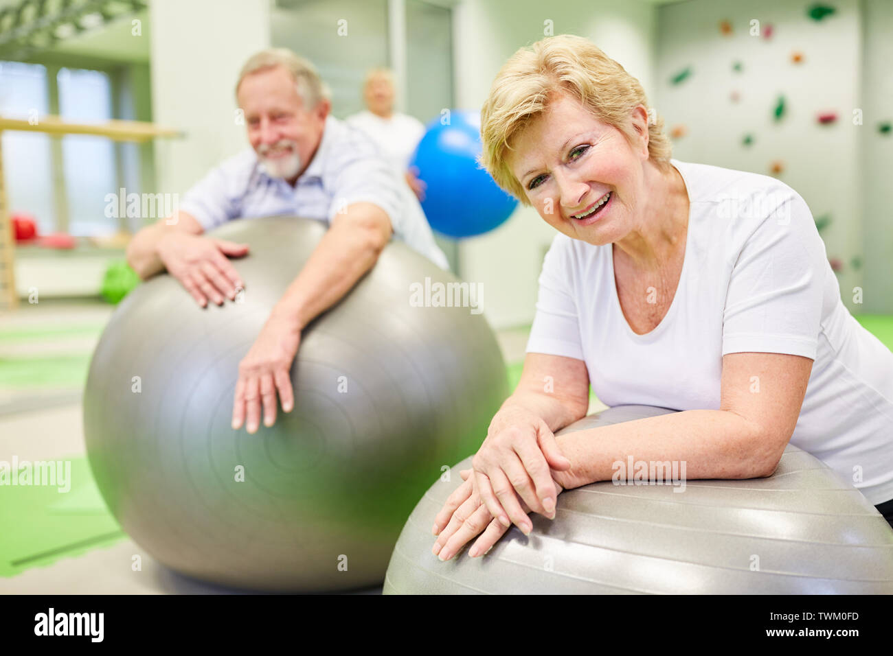 Vital senior couple with gym ball pauses at the back school in ...
