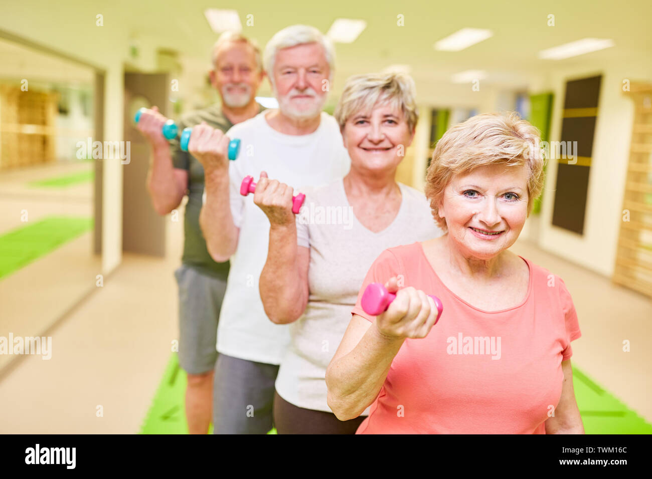 Group of seniors in a fitness class during training with dumbbells to ...