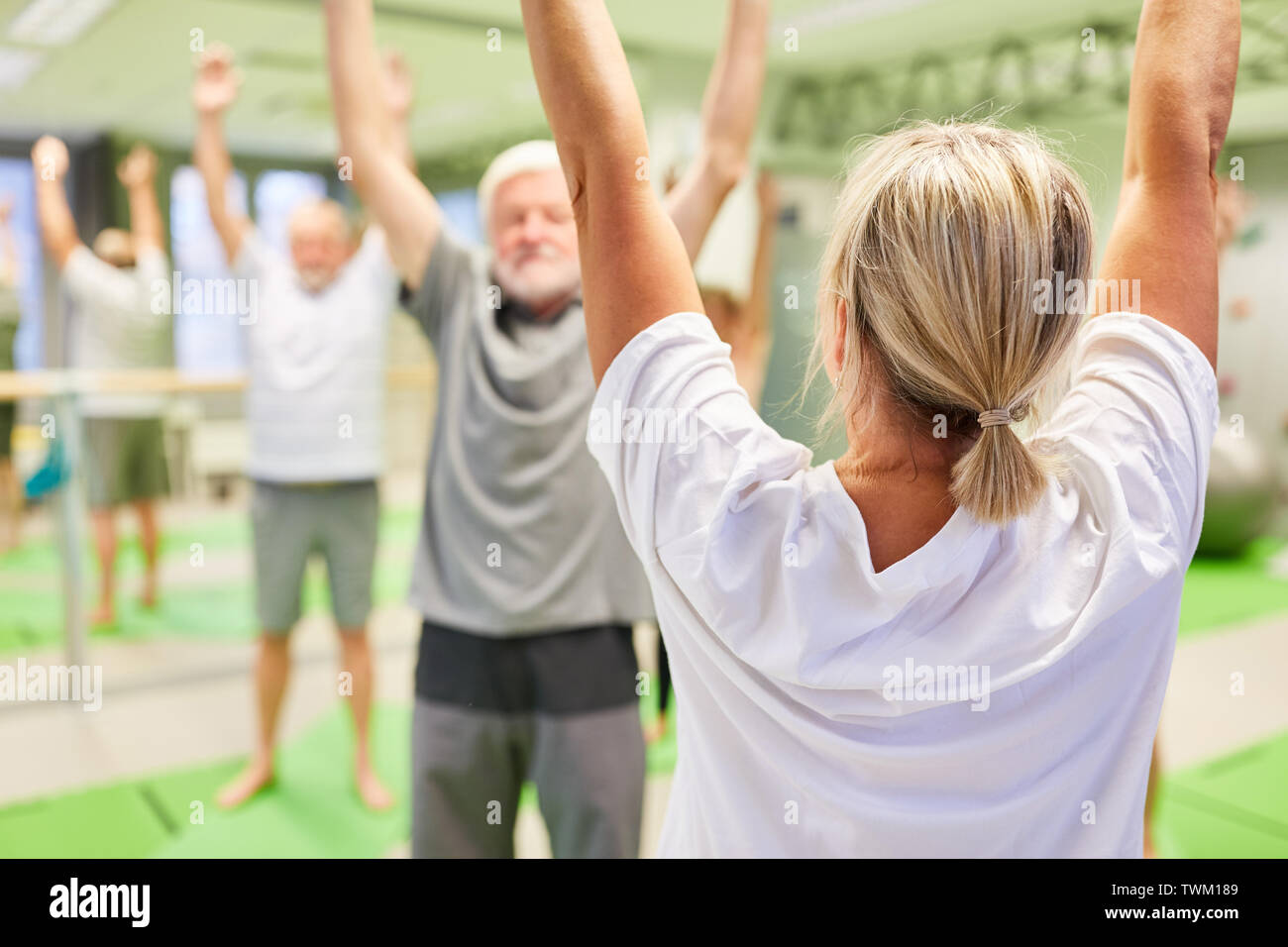 Group of seniors doing back exercises together with physiotherapist in ...