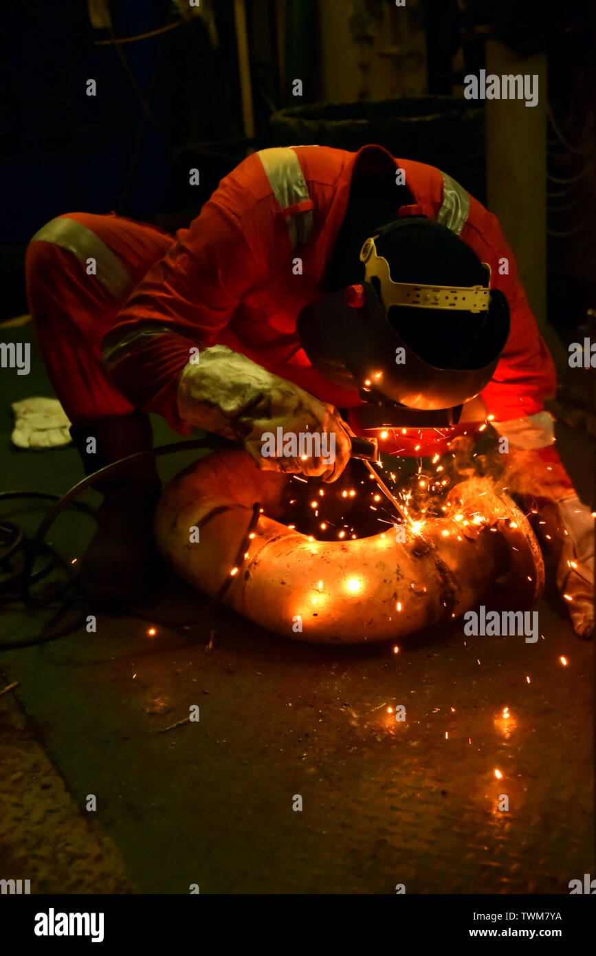 welder and his helper fabricate pipe in a workshop wearing with ...