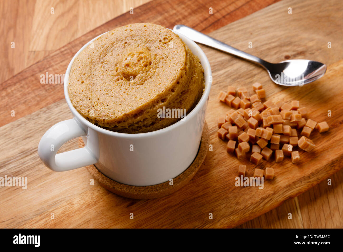 Delicious fudge sponge pudding shot on a wooden board with a hand full ...