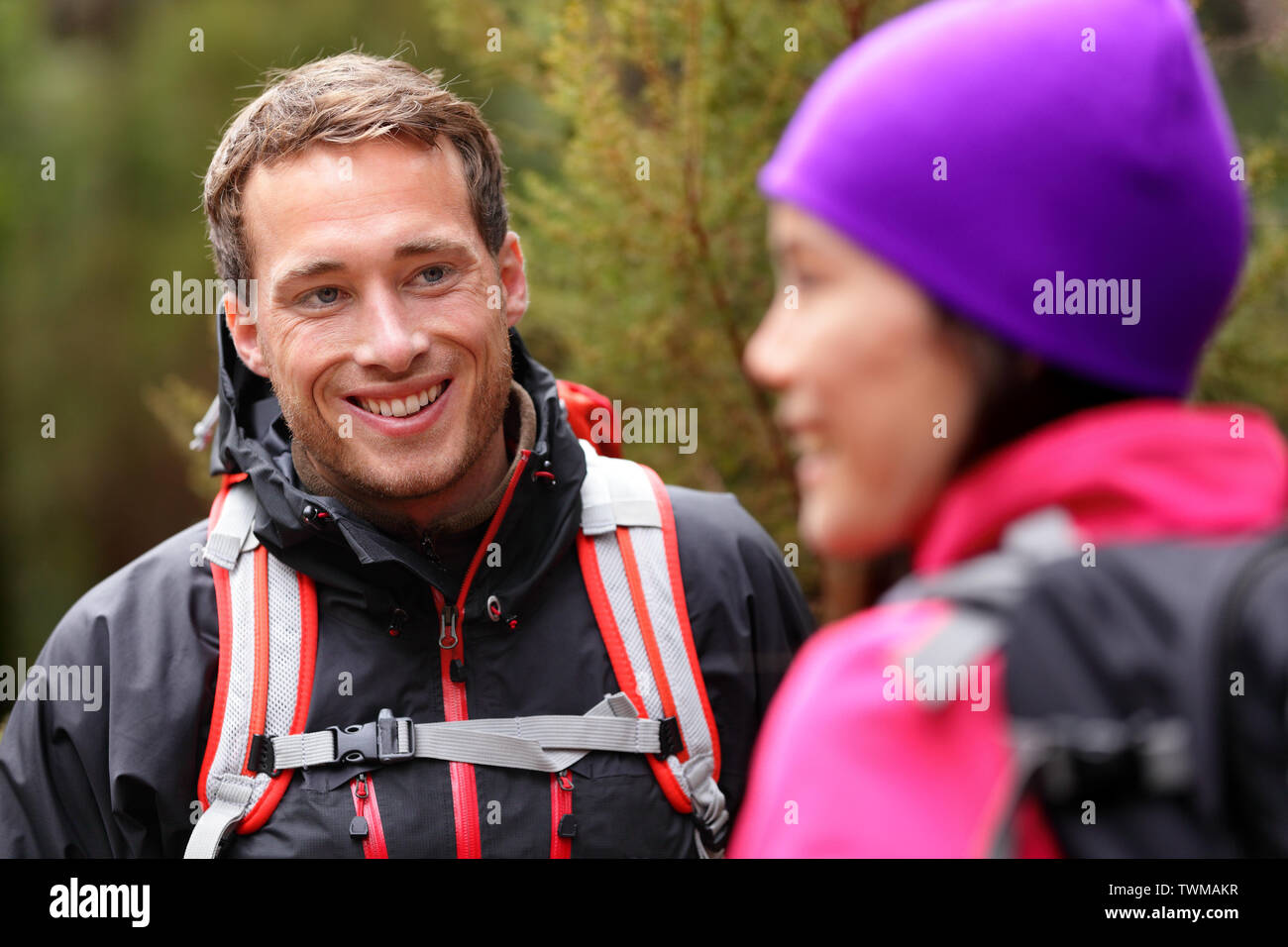 Male hiker portrait in forest talking with woman wearing backpack and ...