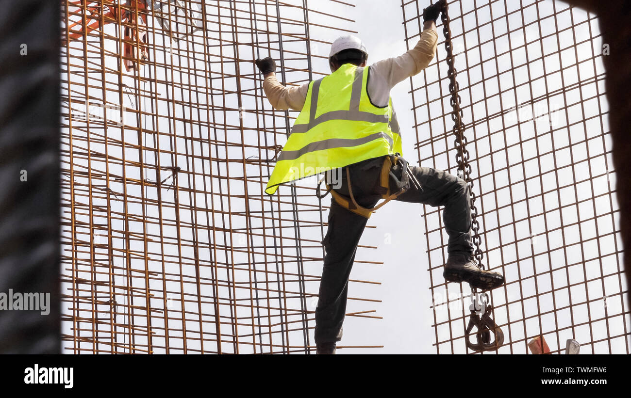Construction workman in a building site dangling in the air from a ...