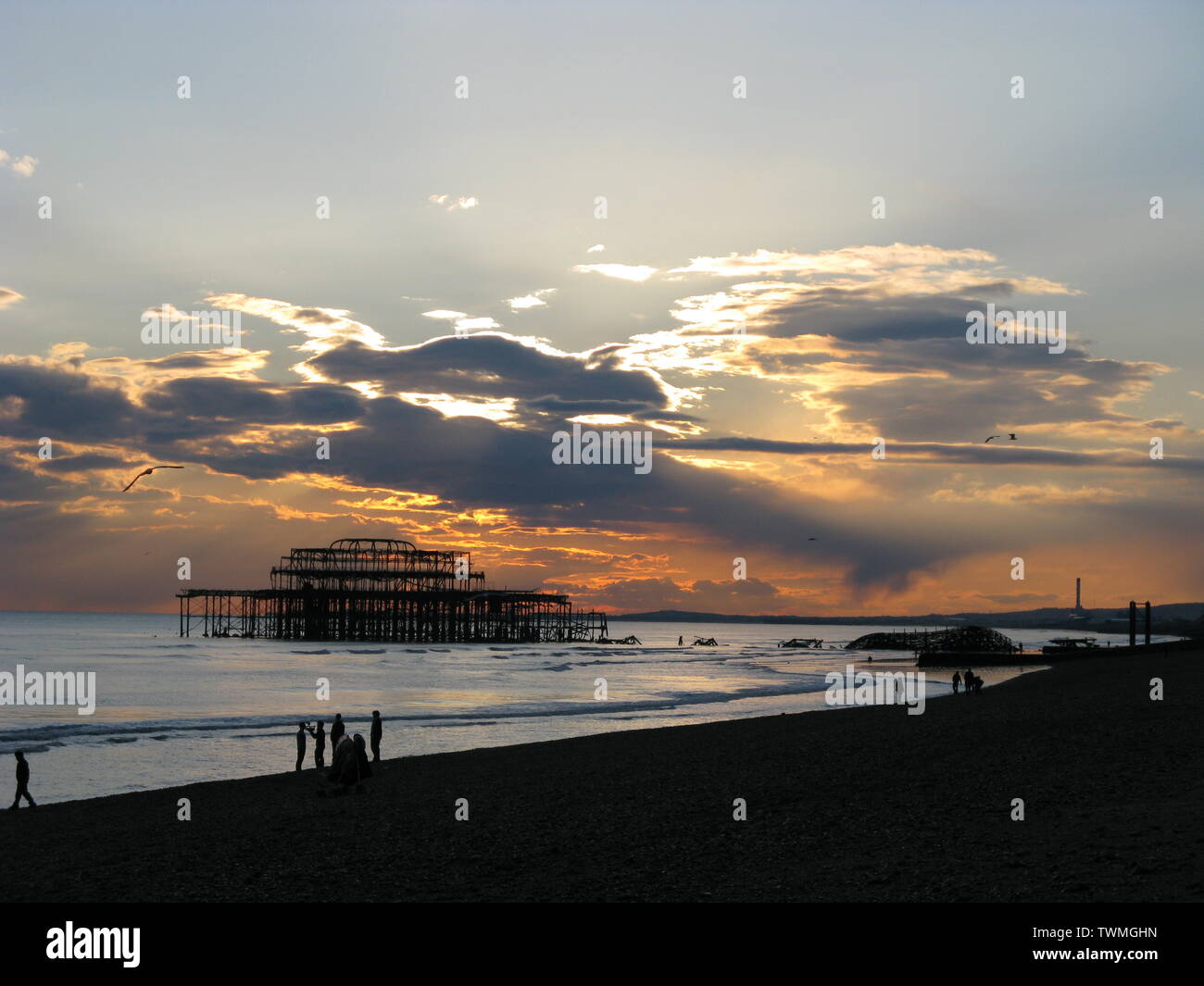 Sunset through clouds over Brighton Beach pier (abandoned) and beach ...