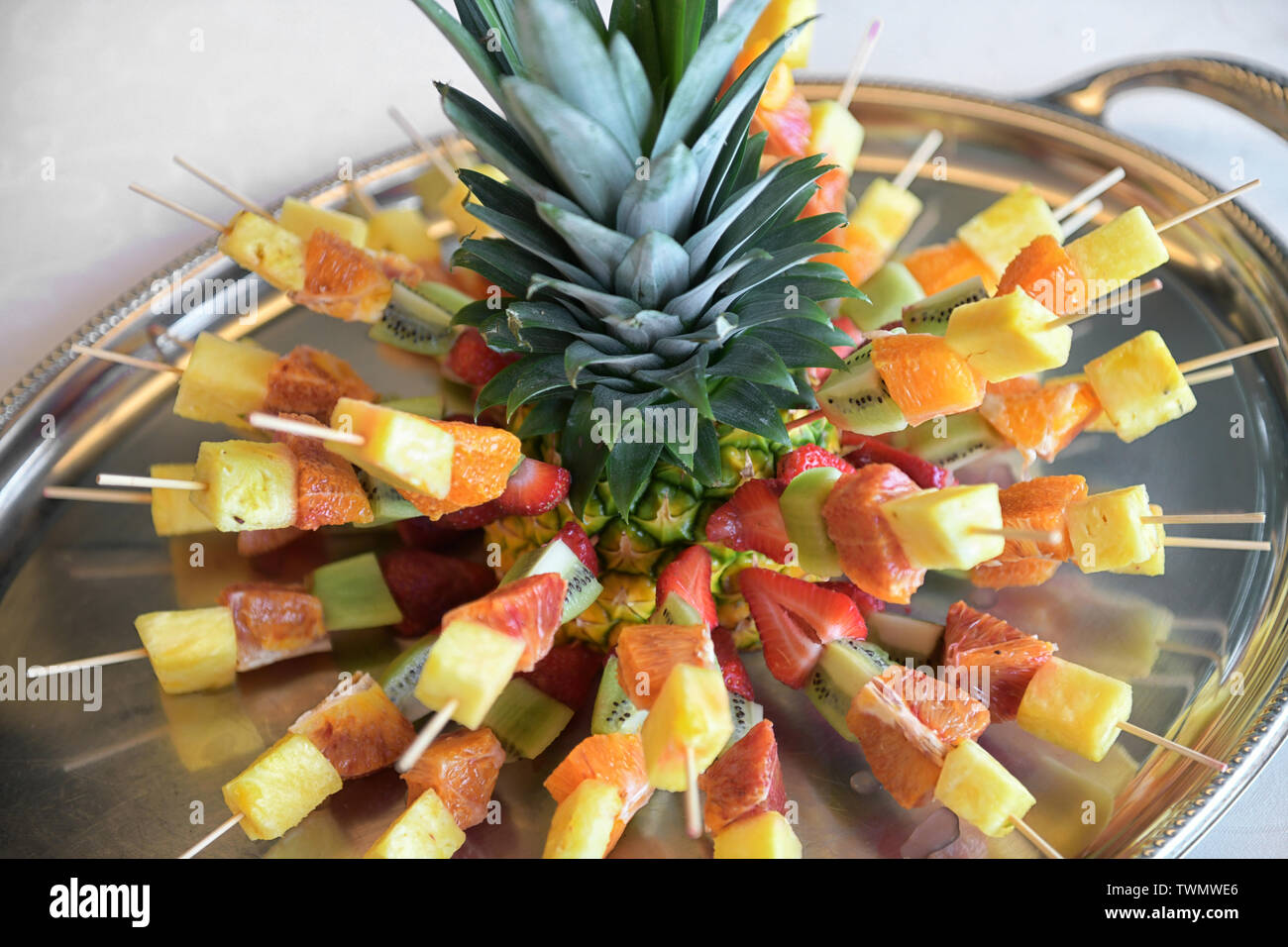 Fresh tropical fruit kebabs or skewers radiating from a pineapple with ...