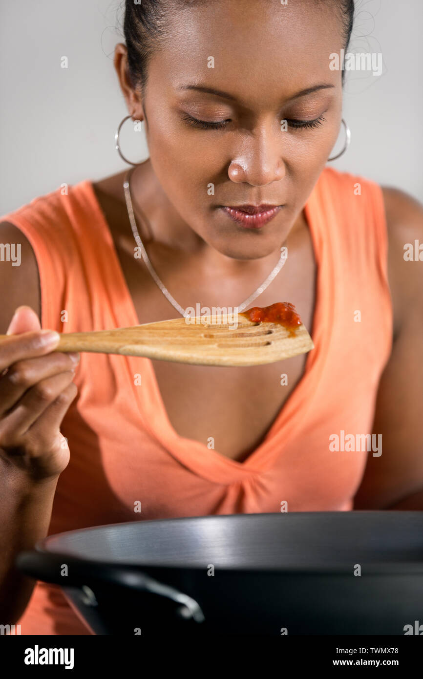 Beautiful young Indonesian woman testing the food in the kitchen Stock ...