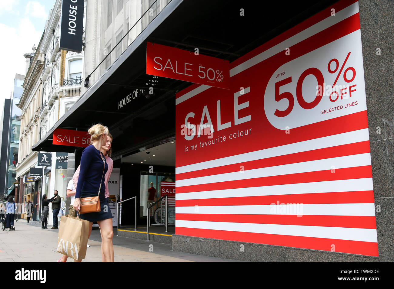 Shoppers walk past a store window display on Oxford Street as summer ...