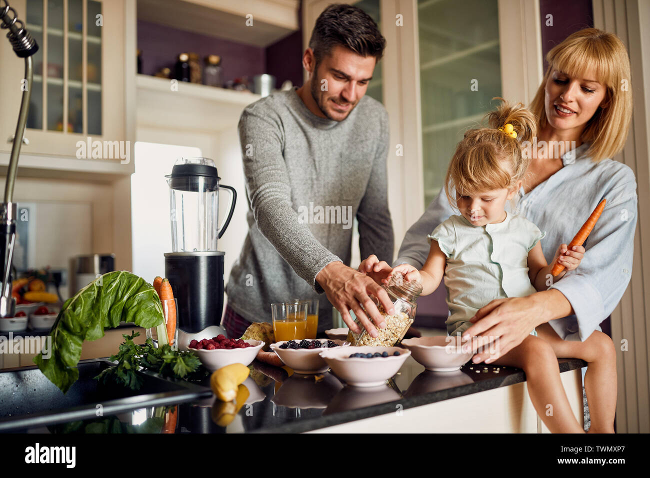 Happy family with girl in kitchen making breakfast together Stock Photo ...