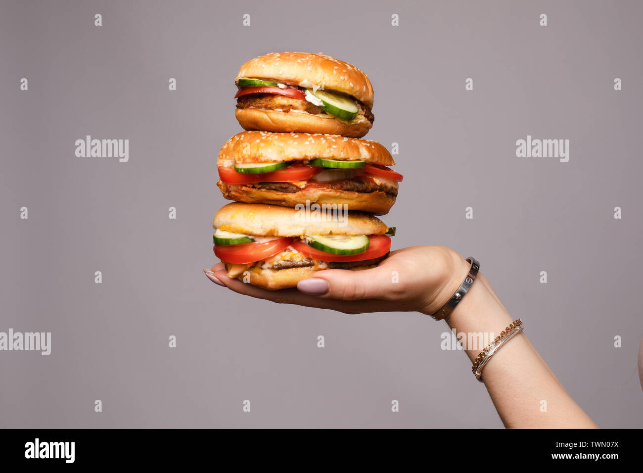 Female hand holding pyramid from three appetizing burger isolated at ...