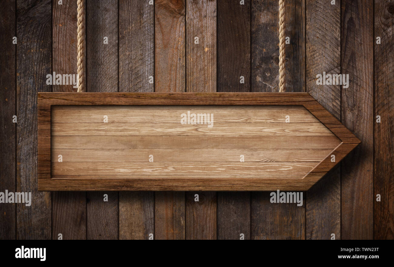 Arrow shaped sign hanging on ropes with wood planks background Stock ...