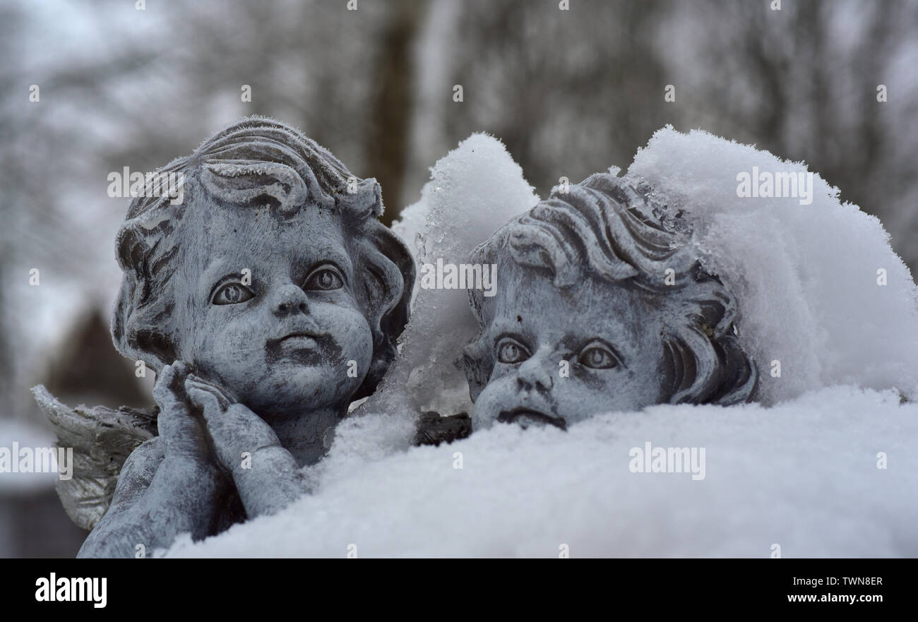 Two little angel made of stone covered with snow in winter Stock Photo ...