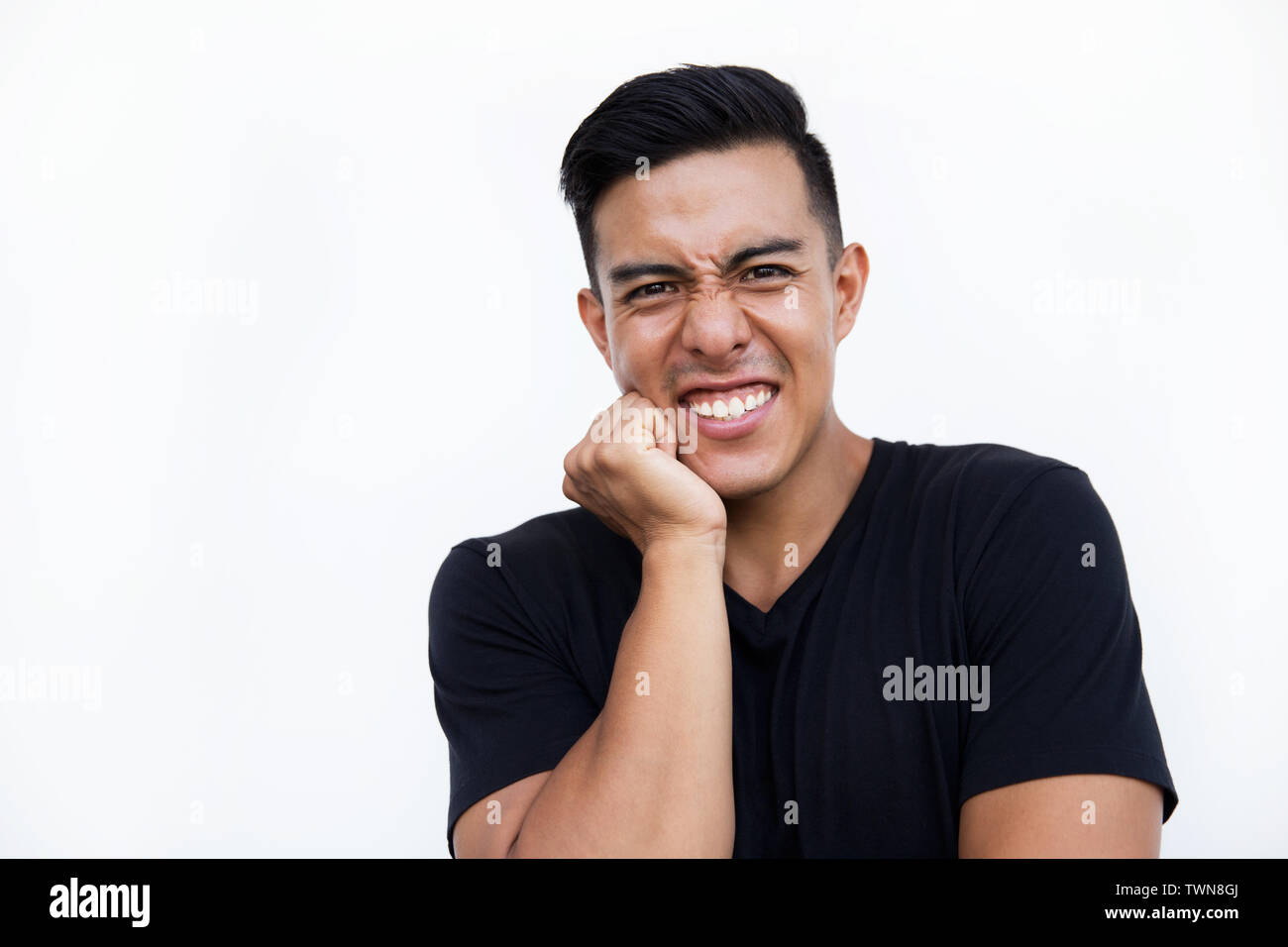 Frustrated young man holding hand on his cheek while standing on white ...