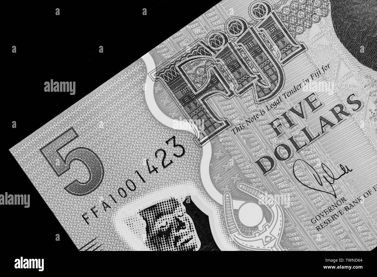Five Fijian dollars banknote on a black background close up. Black and ...