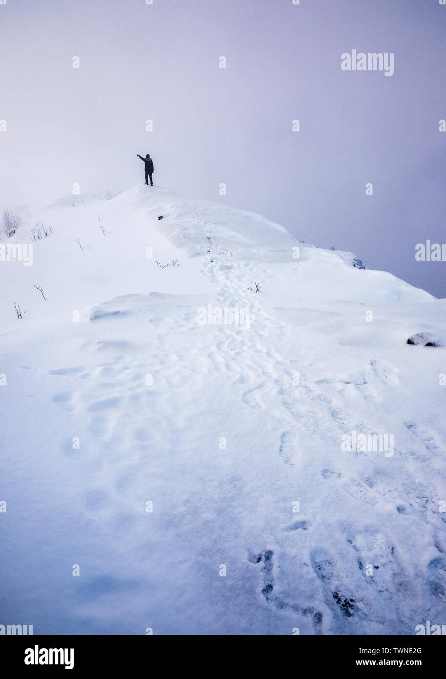 Man stand pointing on snow steep ridge with footprint Stock Photo - Alamy