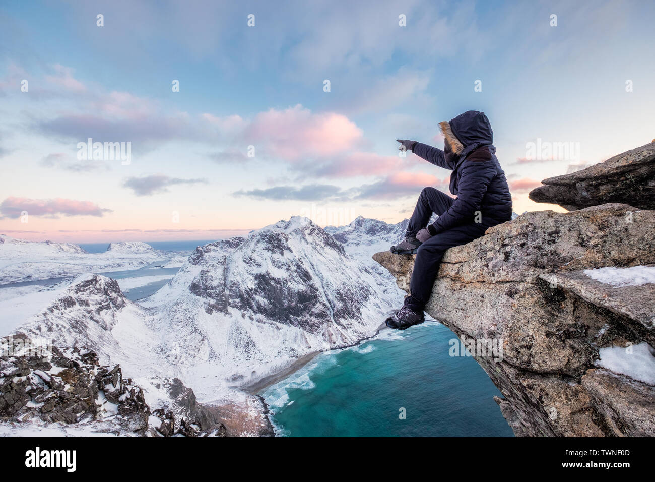 Mountaineer sitting on rock at the peak mountain of arctic coastline at ...