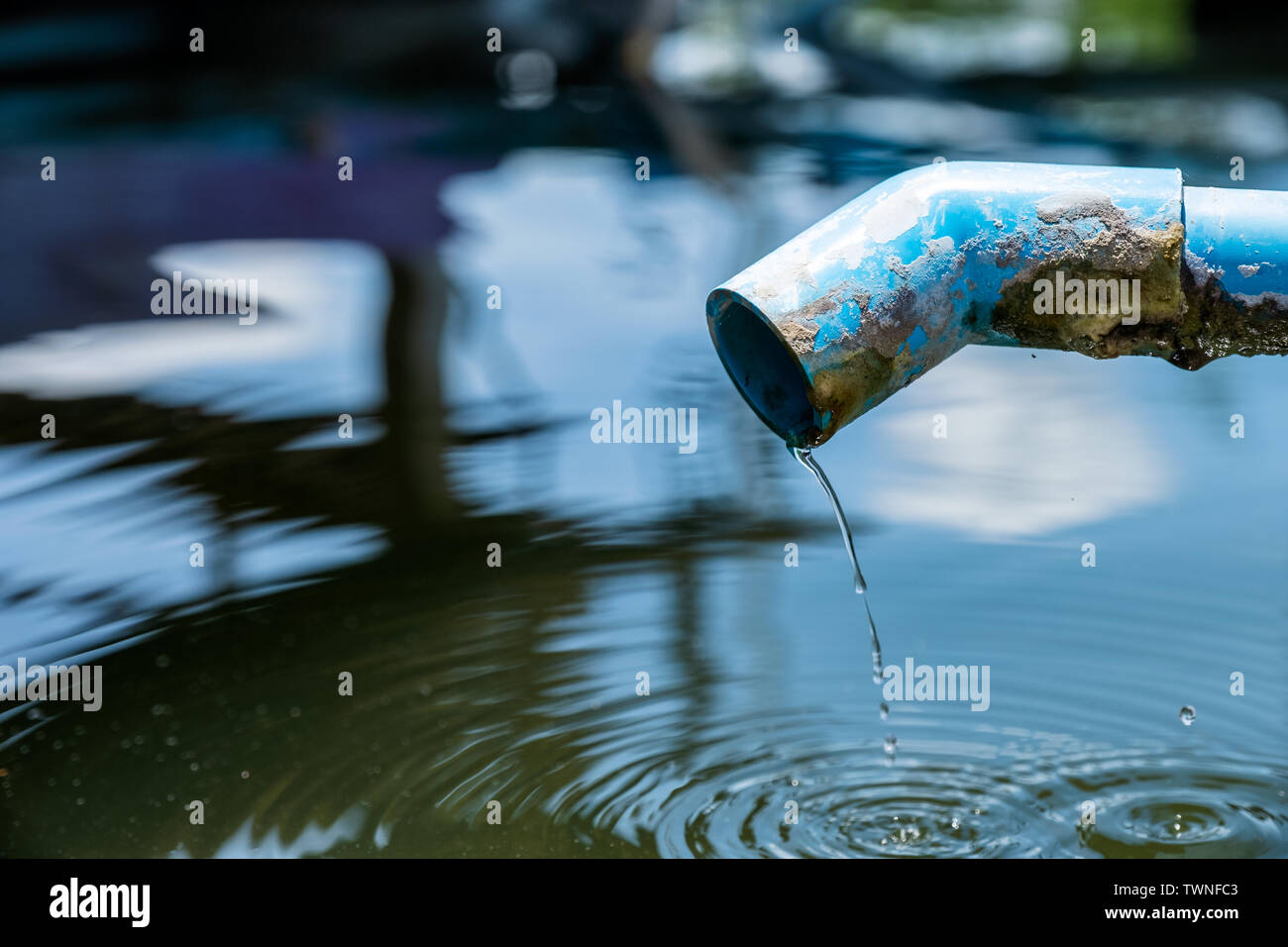 Old blue pipe a water drop in pond with ripple Stock Photo - Alamy