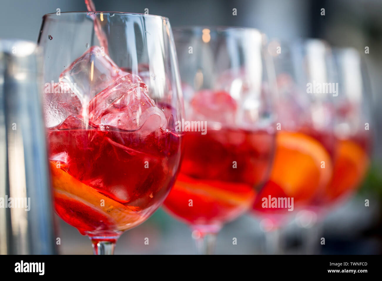 glasses of cocktails on the bar. bartender pours a glass of sparkling wine with Aperol ...
