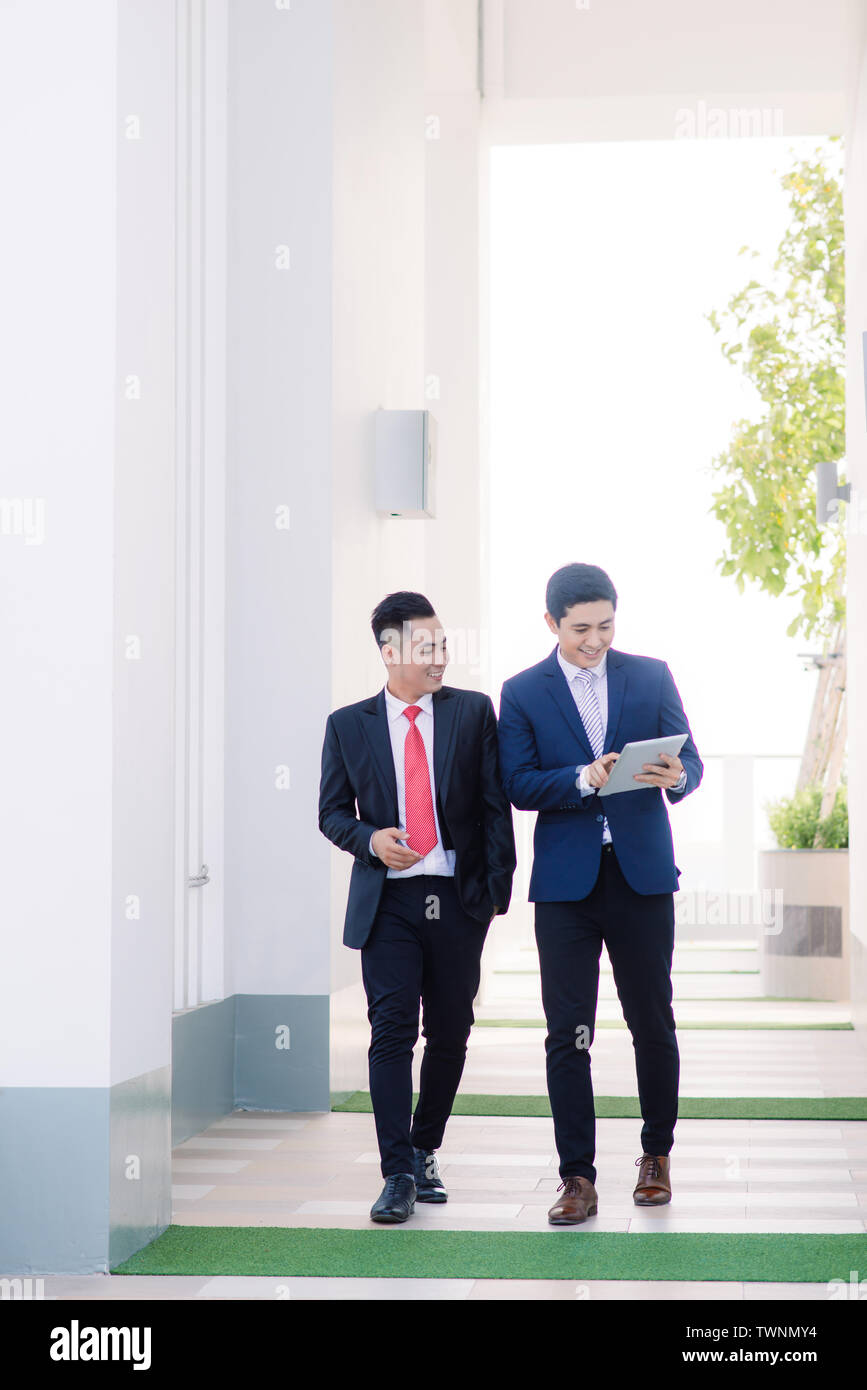 Two Vietnamese male coworkers talking and smiling Stock Photo - Alamy