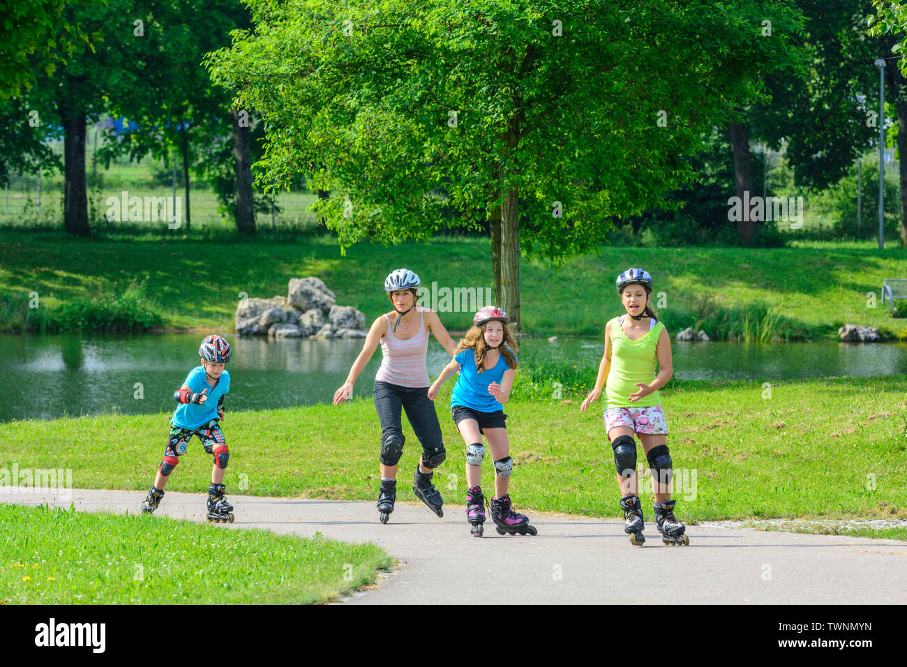 Young family doing a tour on inline skates in urban park at a sunny ...