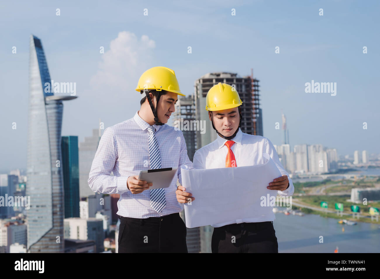 View of a Engineer and worker watching blueprint on construction site ...