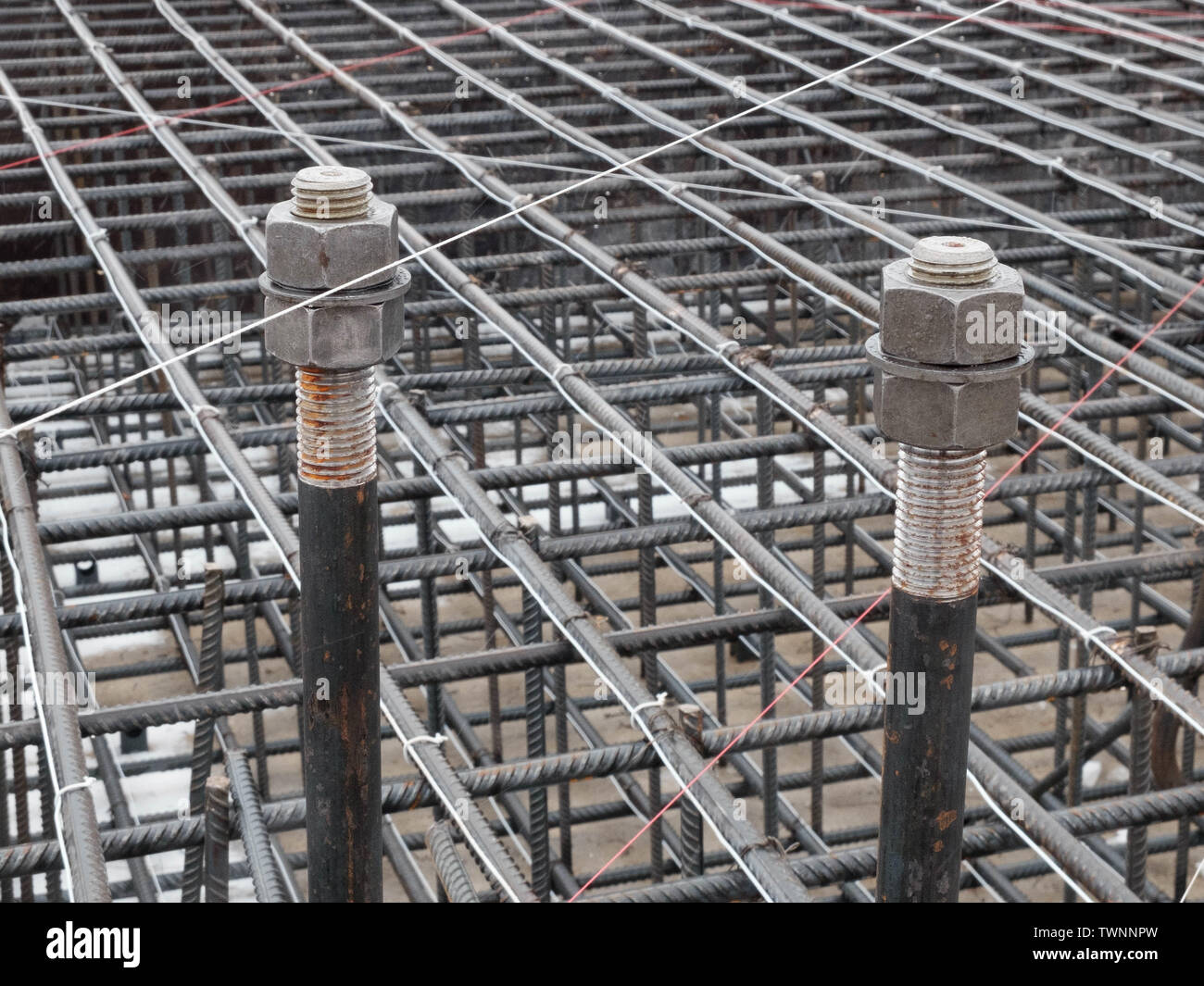 Two steel anchor bolts with screw nuts and steel grid on tower crane ...
