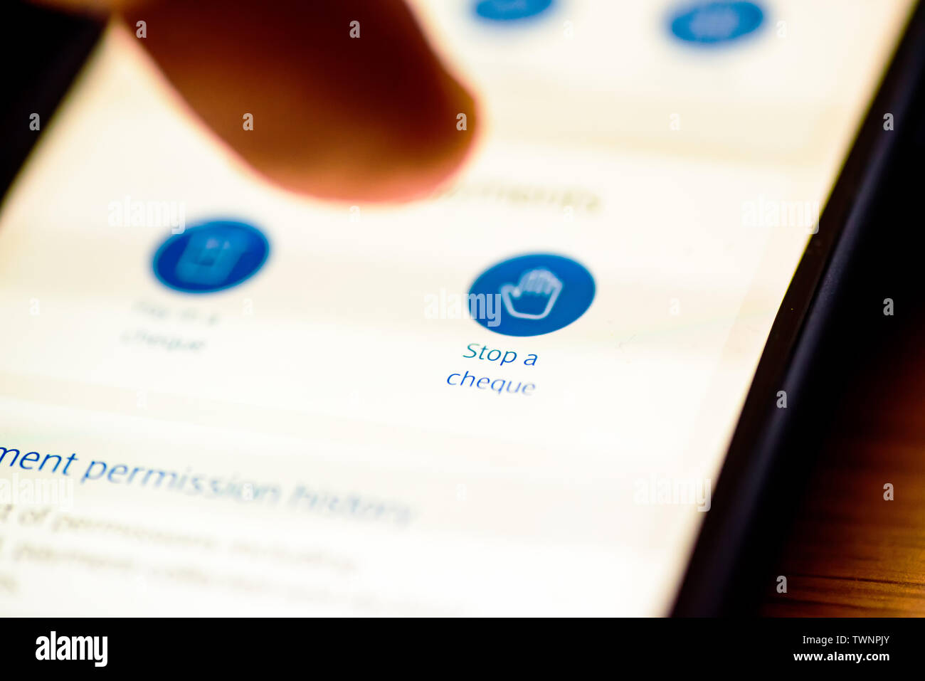Stop a cheque button on smartphone app screen closeup with human finger ...