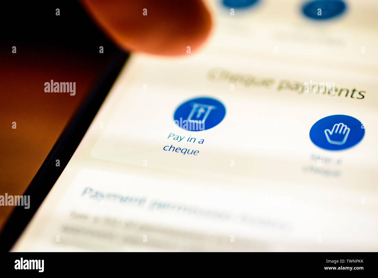 Pay in cheque button on smartphone app screen closeup with human finger ...
