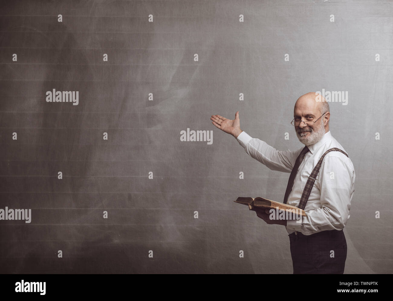 Smiling confident professor teaching and pointing at the blackboard ...