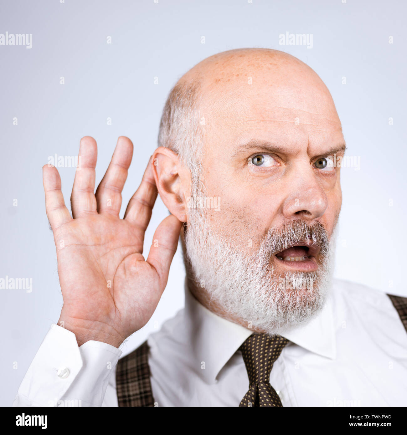 Senior businessman keeping a hand next to his ear and overhearing ...