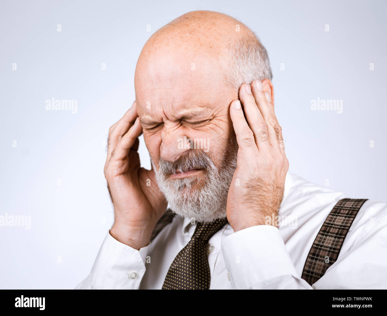 Senior man having a bad headache, he is suffering and feeling confused ...