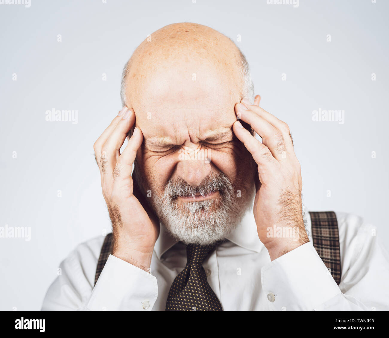 Senior man having a bad headache, he is suffering and feeling confused ...