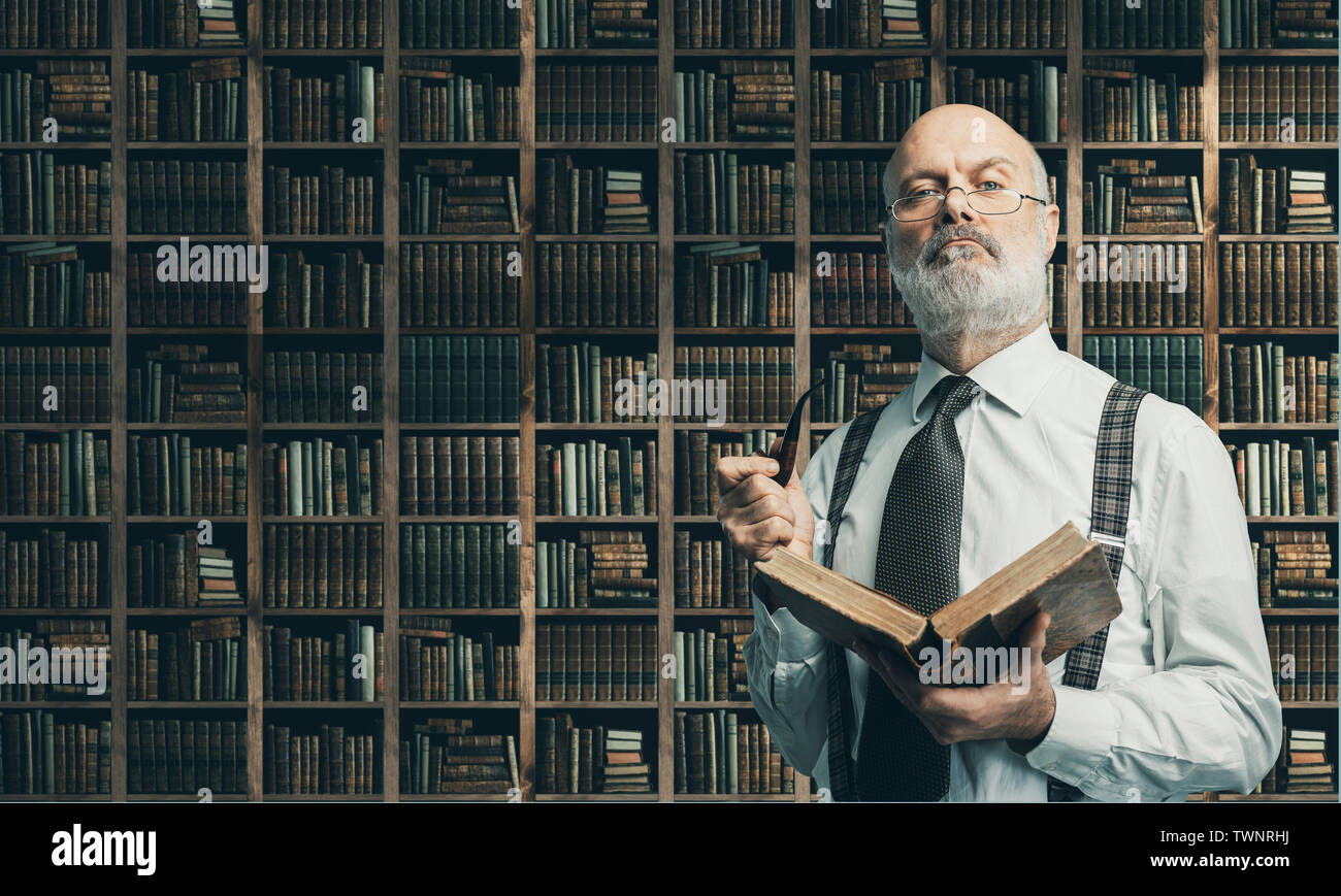 Senior academic professor reading an old book in the library, knowledge ...