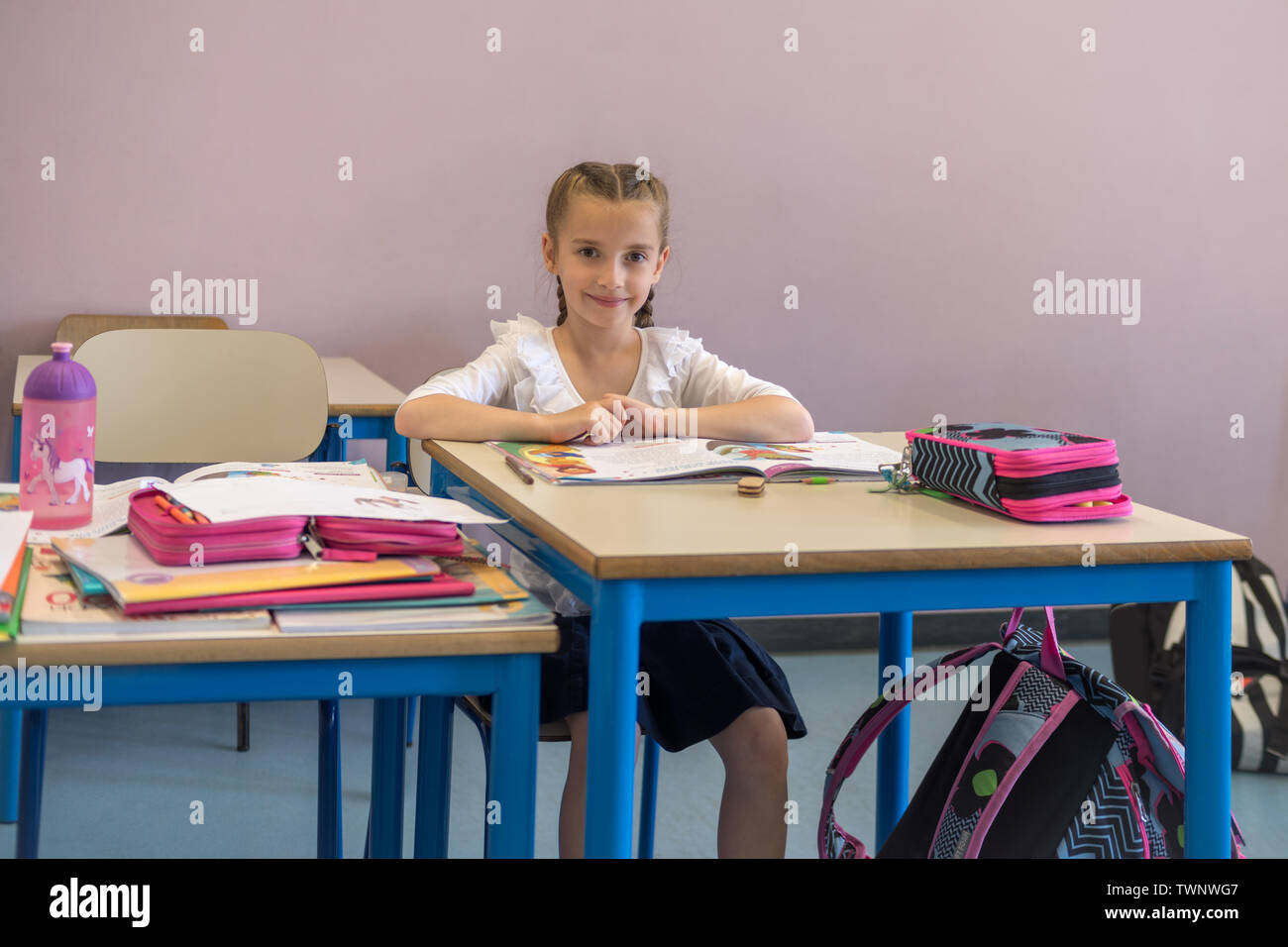 Pretty elementary school girl working on assignment in classroom Stock ...