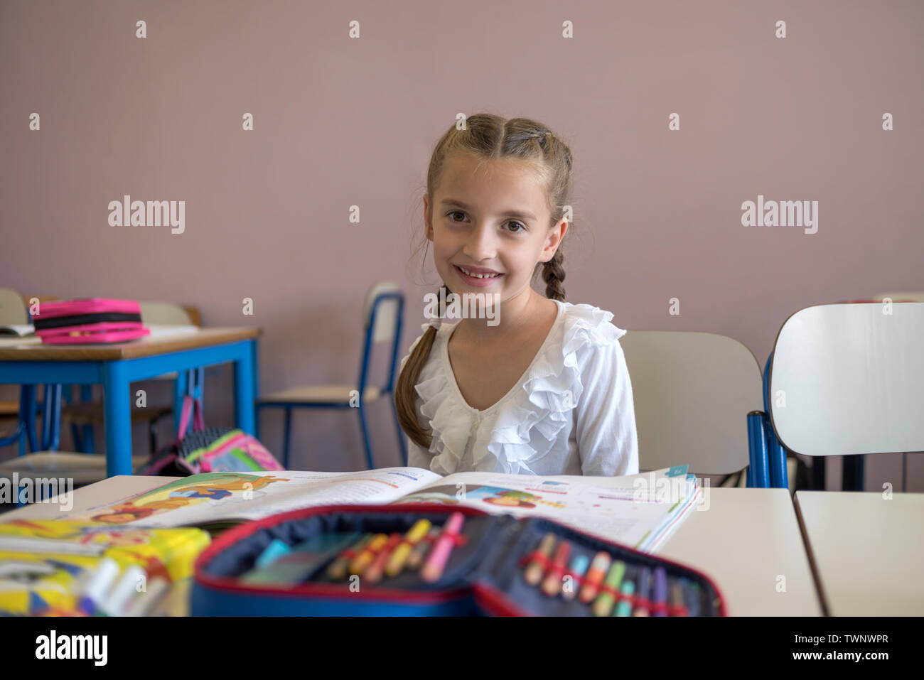 Pretty elementary school girl working on assignment in classroom Stock ...