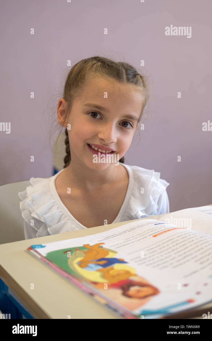 Pretty elementary school girl working on assignment in classroom Stock ...