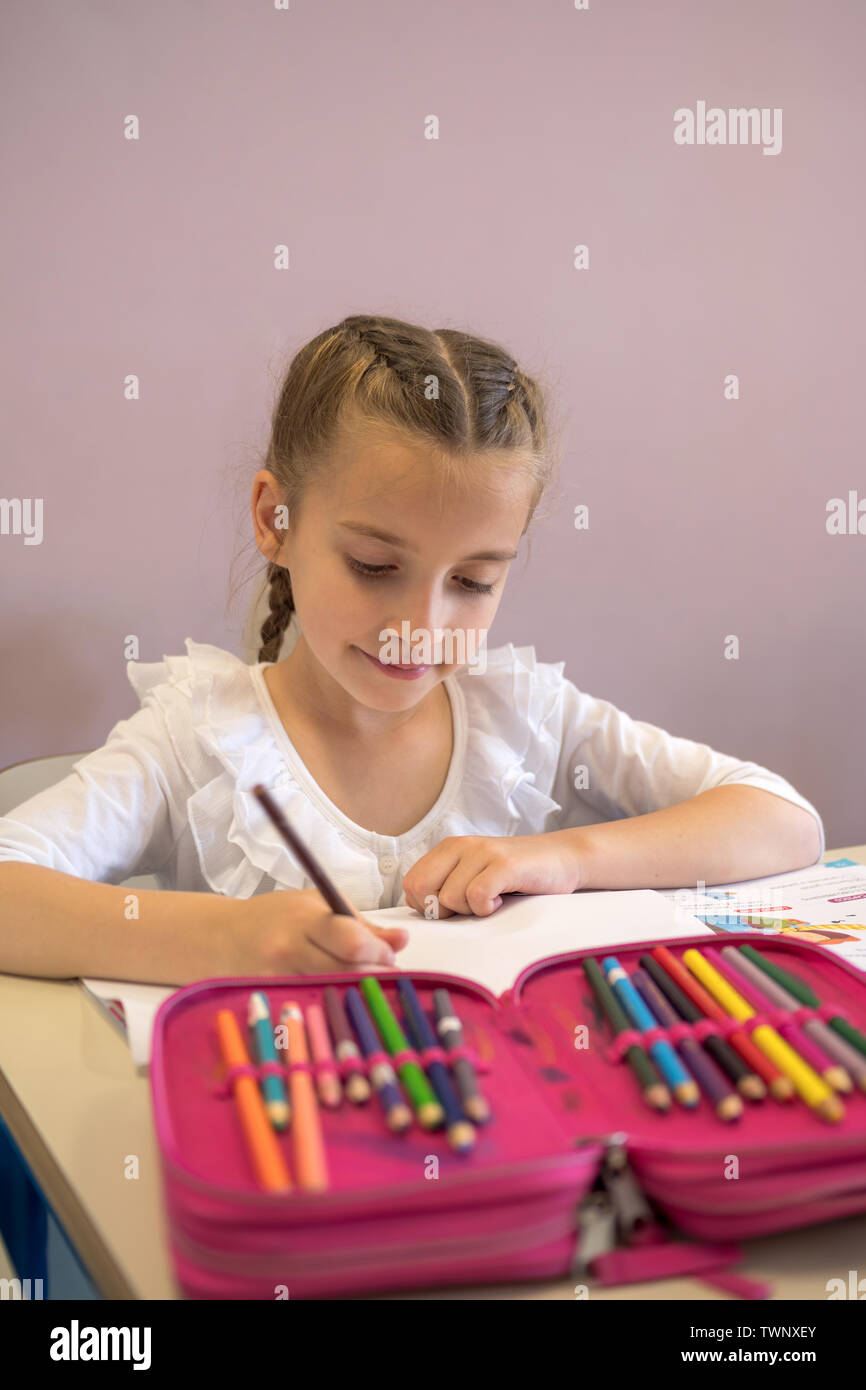 Pretty elementary school girl working on assignment in classroom Stock ...
