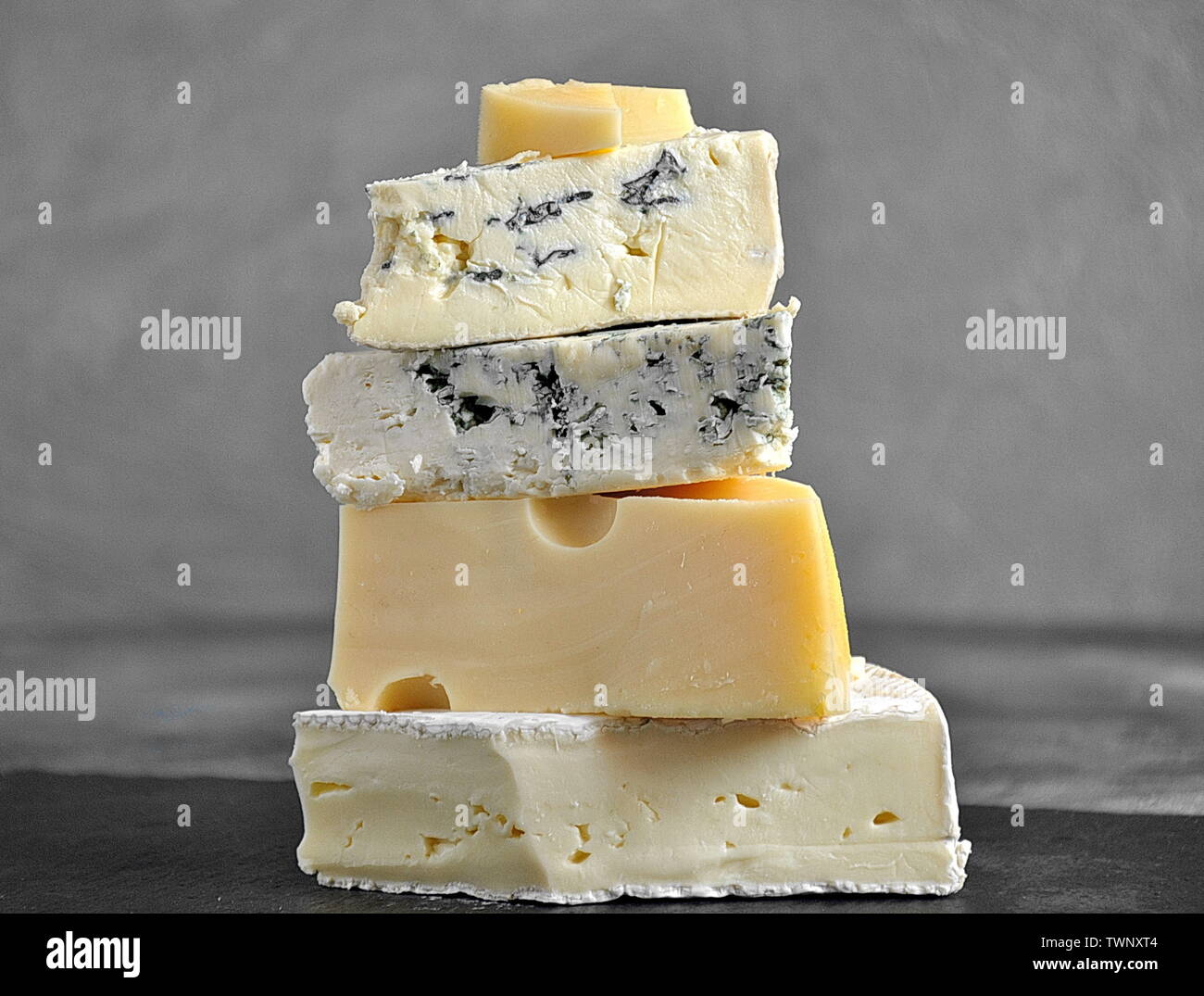 big and small pieces of different types of cheese are lying on a gray ...