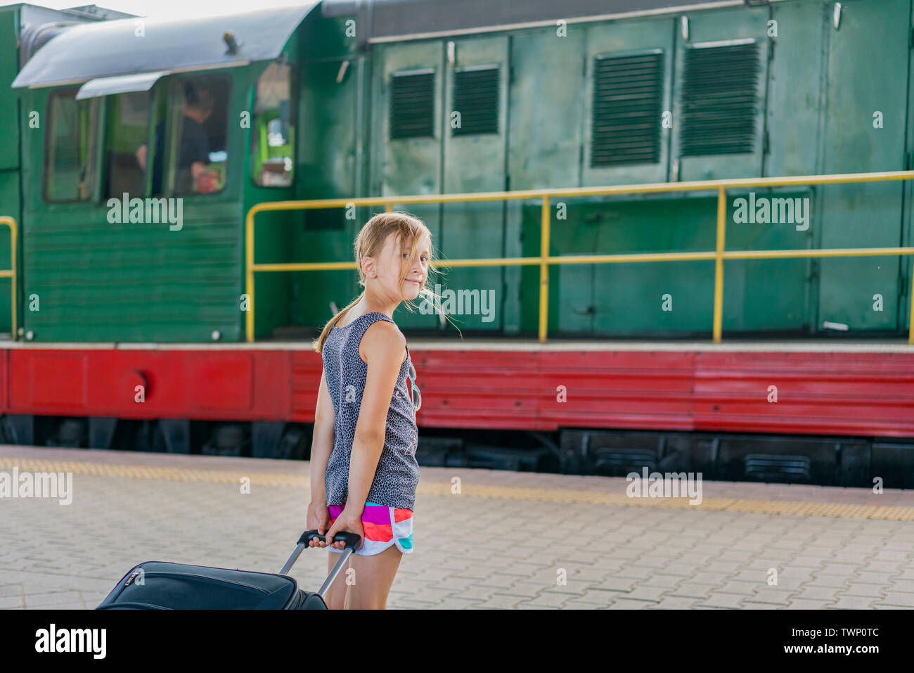 Teenager girl at the train station near the locomotive. girl pulling a ...