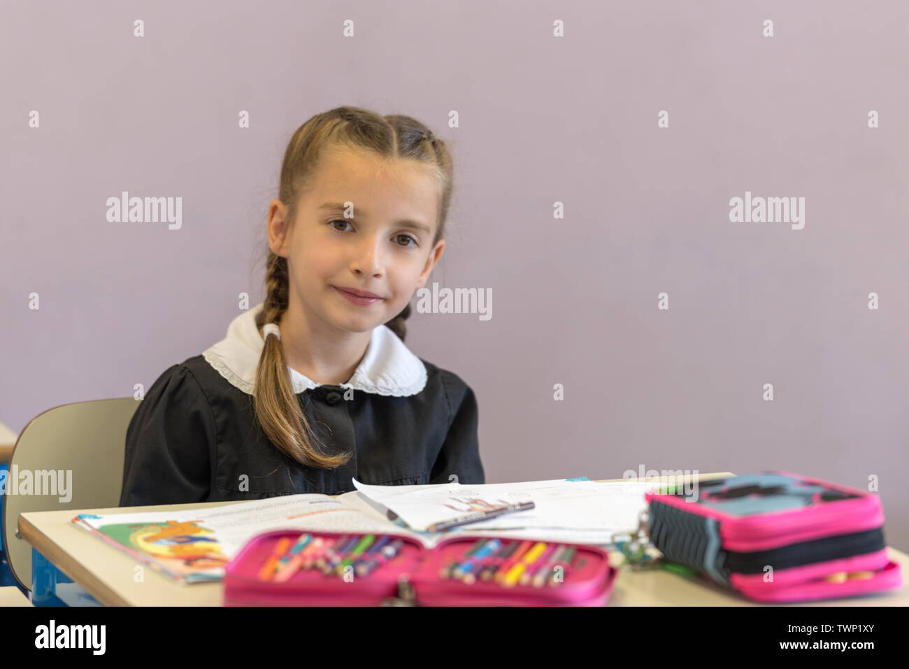 Pretty elementary school girl working on assignment in classroom Stock ...