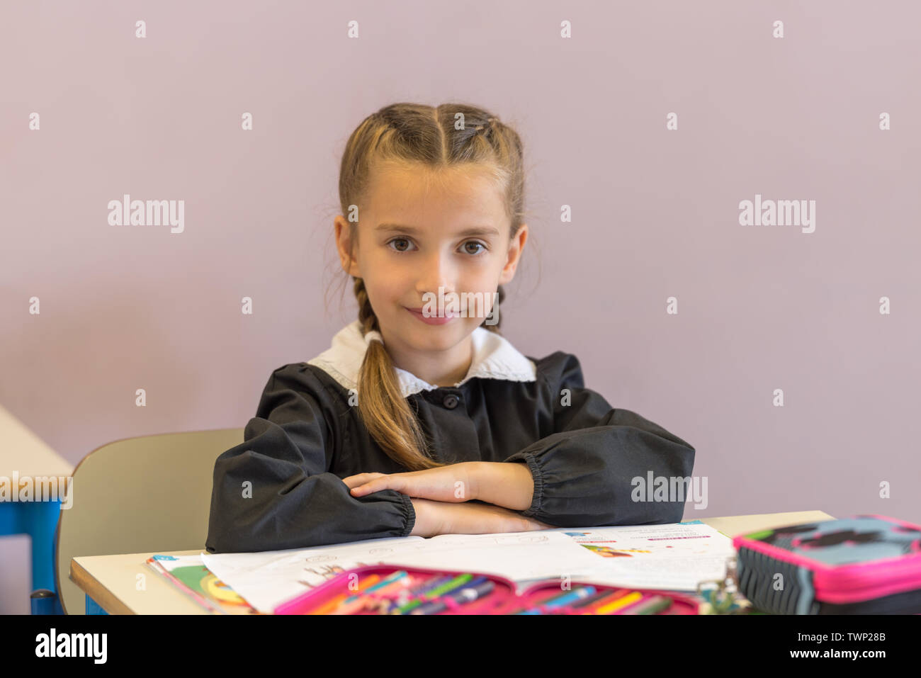 Pretty elementary school girl working on assignment in classroom Stock ...