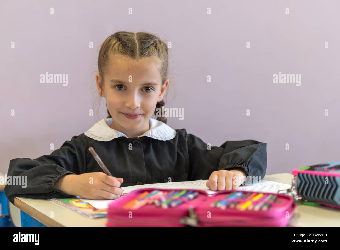 Pretty elementary school girl working on assignment in classroom Stock ...