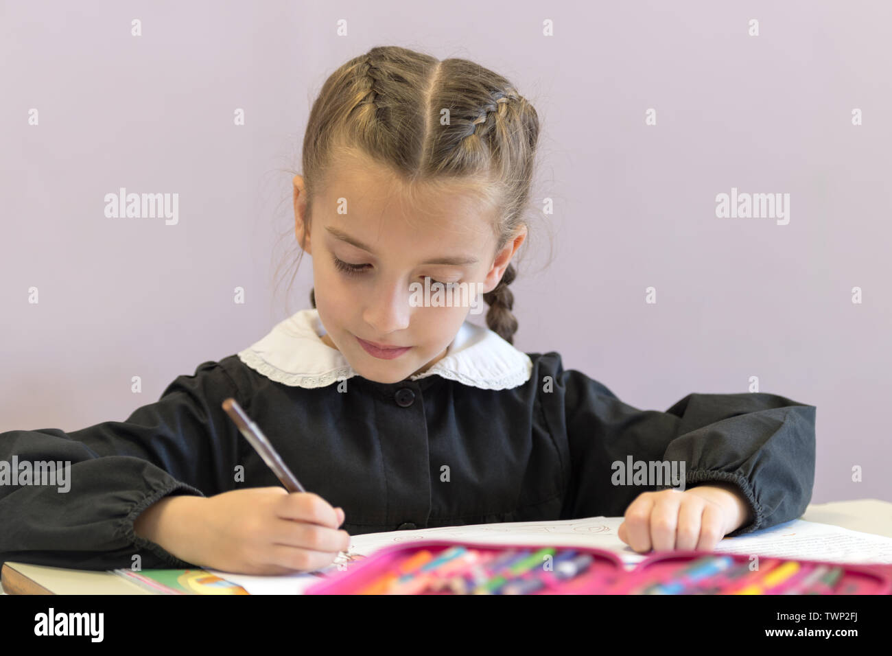 Pretty elementary school girl working on assignment in classroom Stock ...