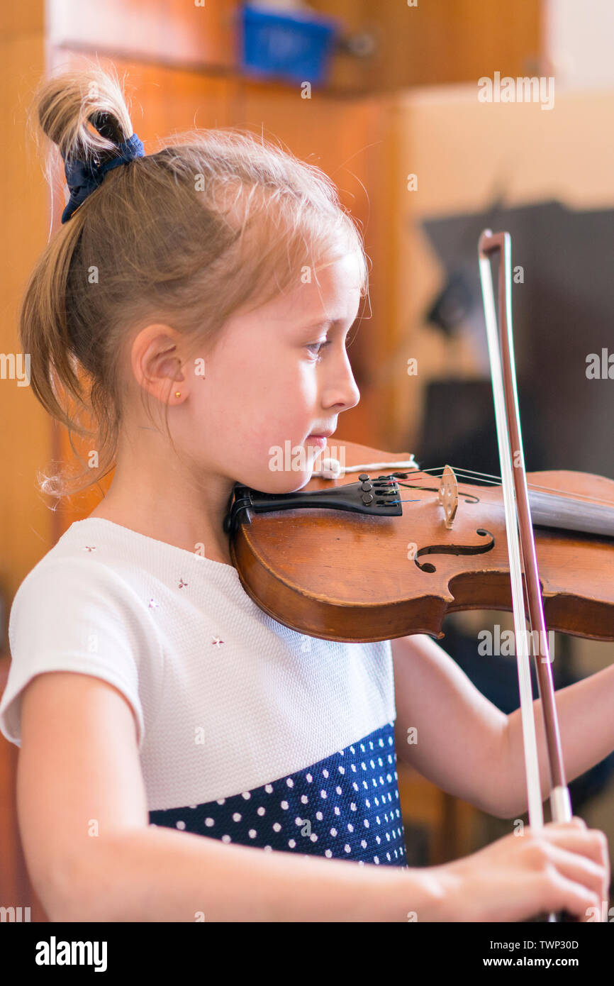 Child, little girl playing violin indoors in music class. vertical ...